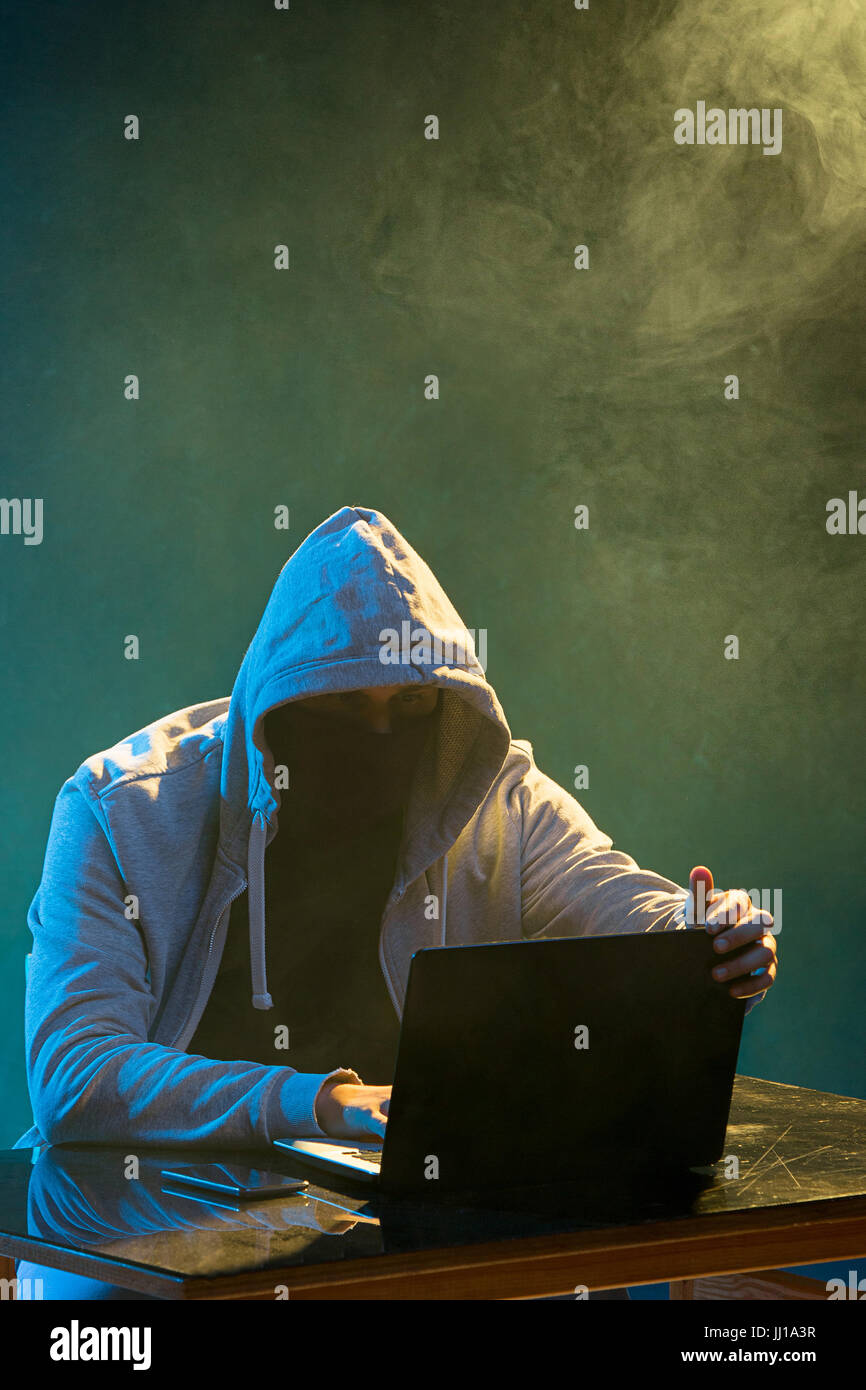 Hooded computer hacker stealing information with laptop Stock Photo - Alamy