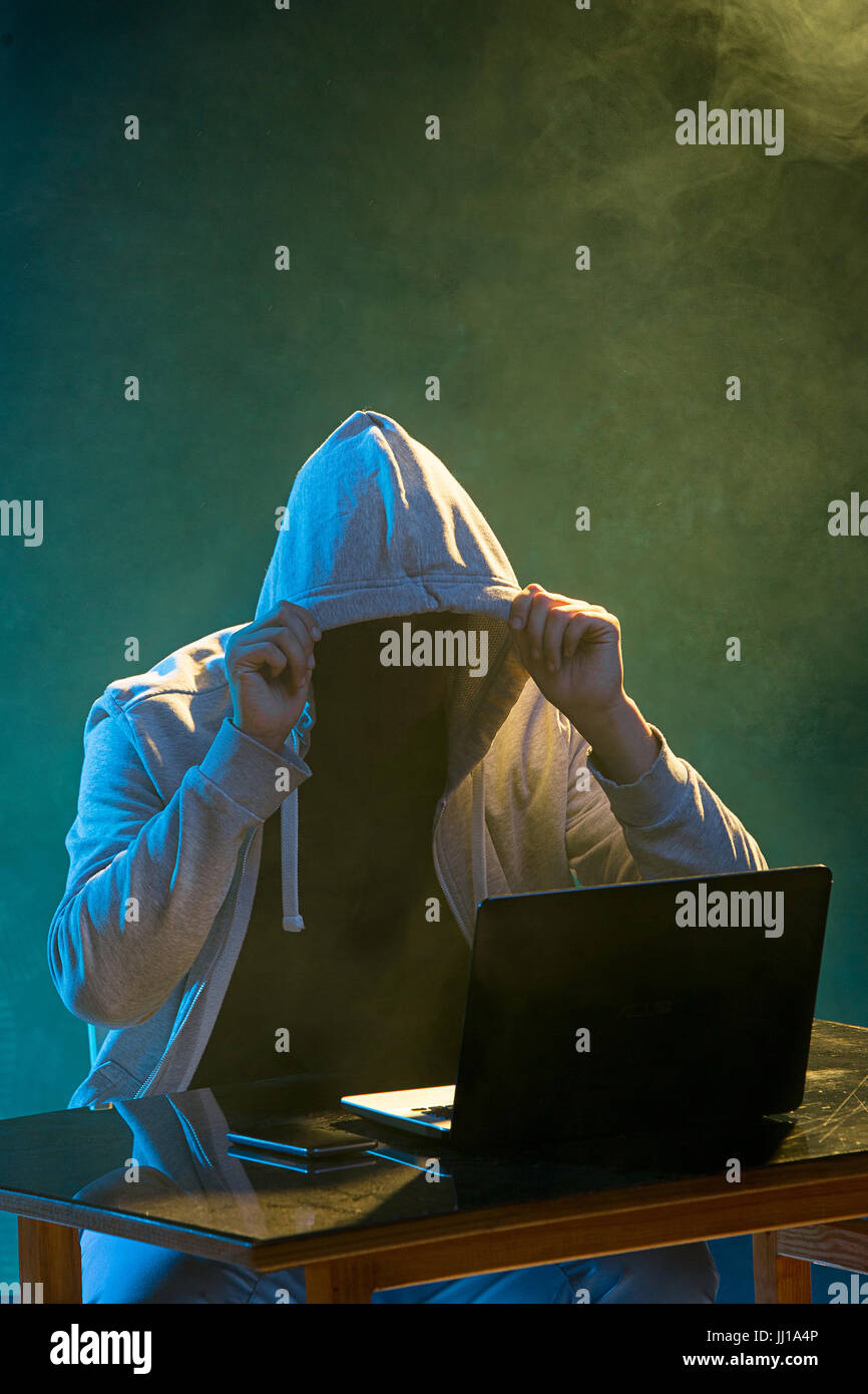 Hooded computer hacker stealing information with laptop Stock Photo - Alamy