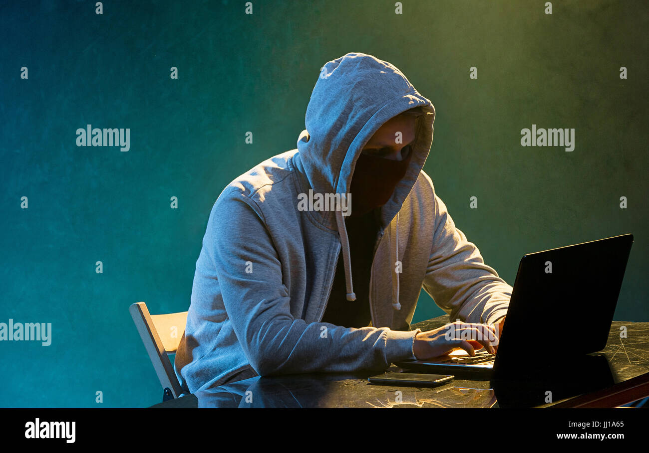 Hooded computer hacker stealing information with laptop Stock Photo - Alamy