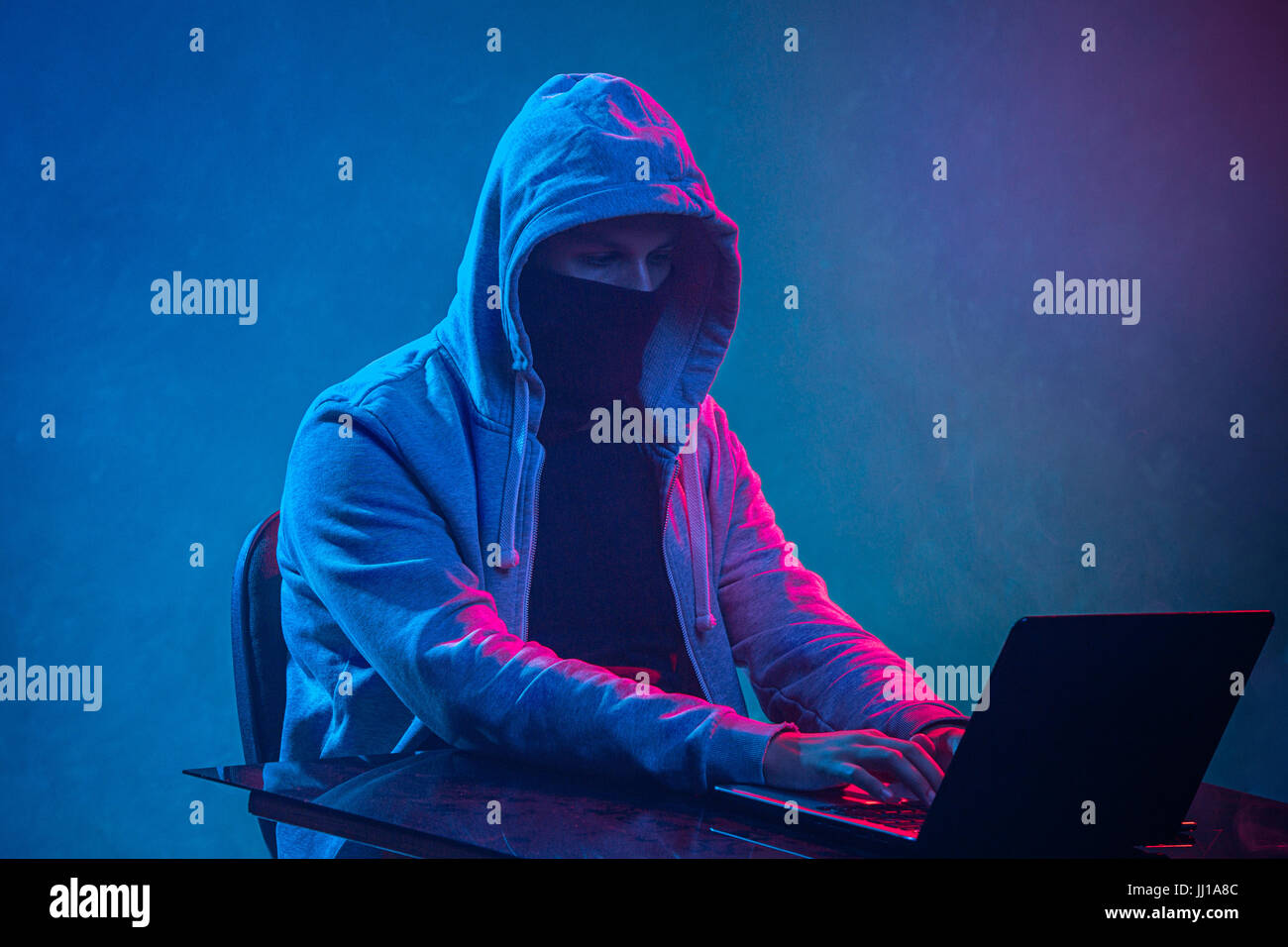 Hooded computer hacker stealing information with laptop Stock Photo - Alamy