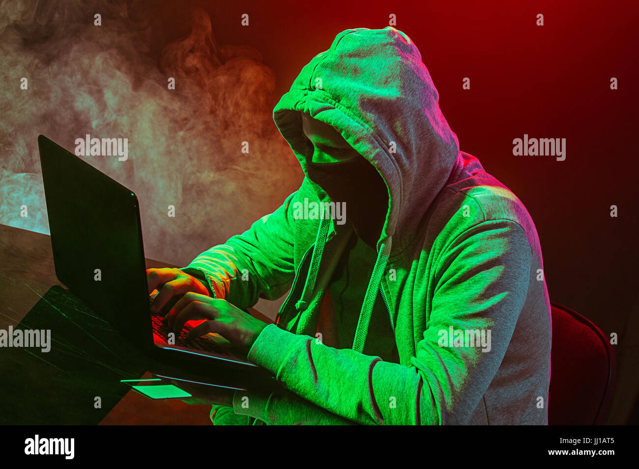 Hooded computer hacker stealing information with laptop Stock Photo - Alamy