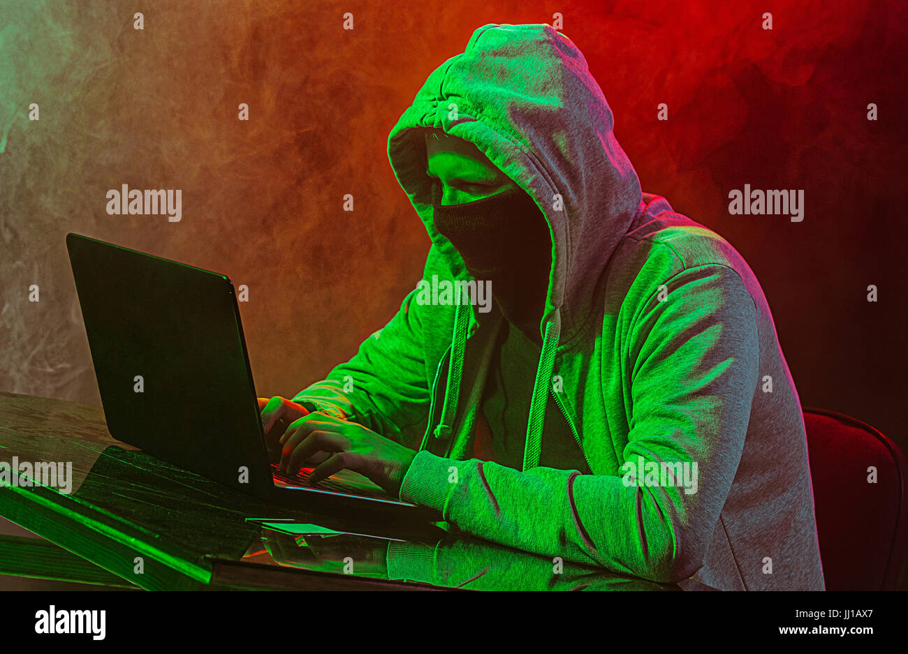 Hooded computer hacker stealing information with laptop Stock Photo - Alamy