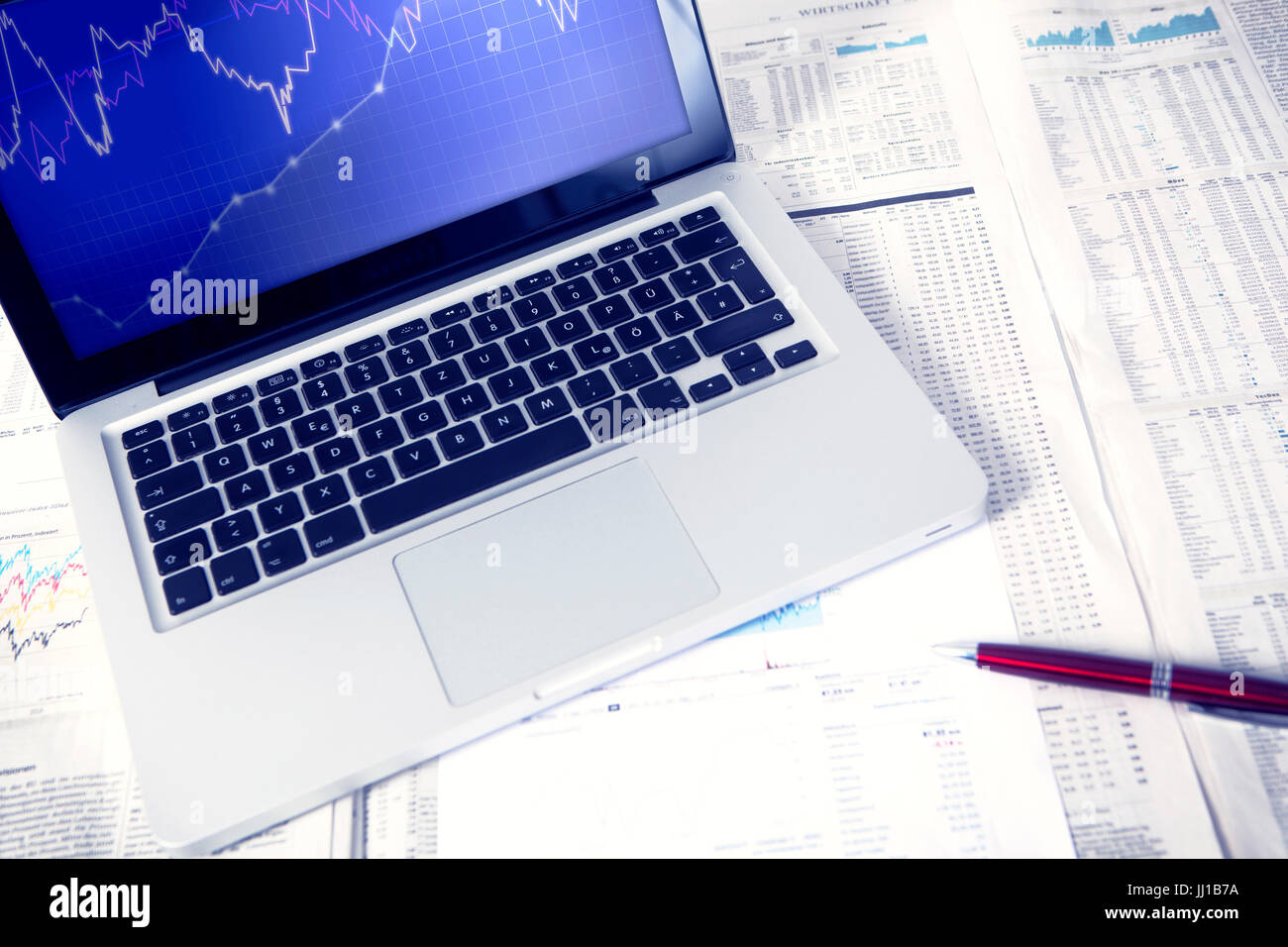 Various documents and papers under a laptop with stock chart Stock ...