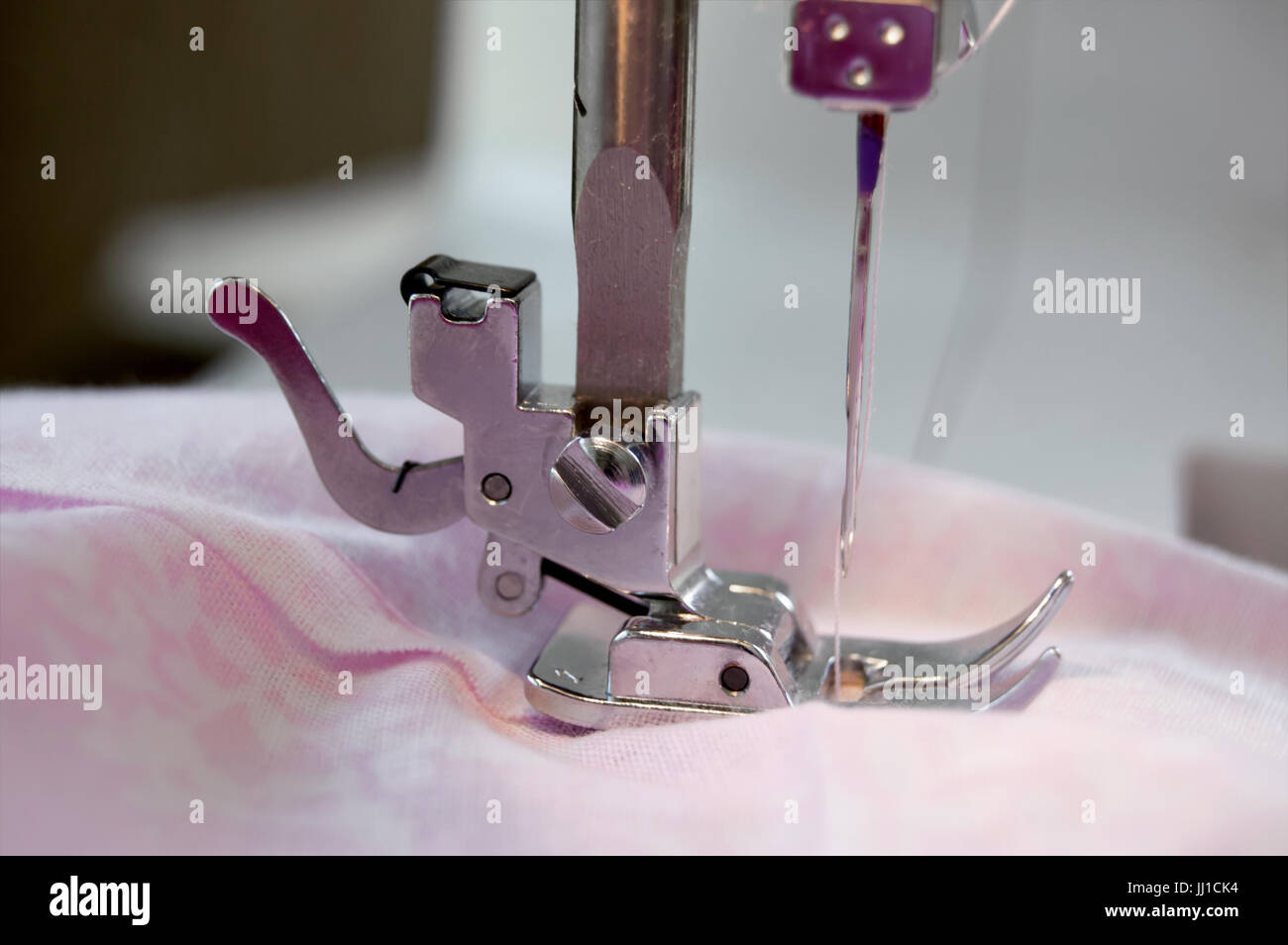 A sew machine needle sewing pink fabric Stock Photo - Alamy