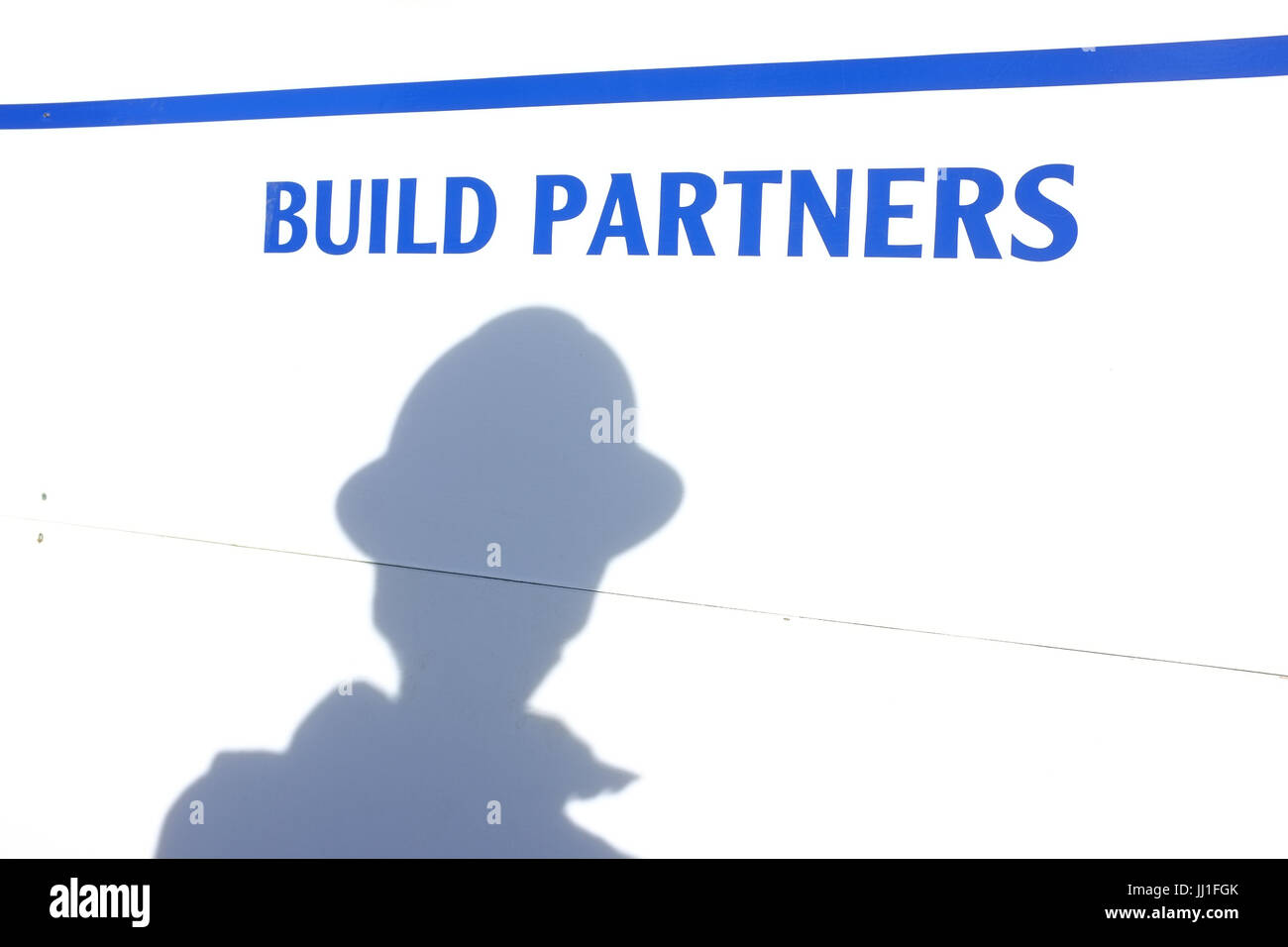 The shadow of a worker's head falls onto a building site sign Stock ...