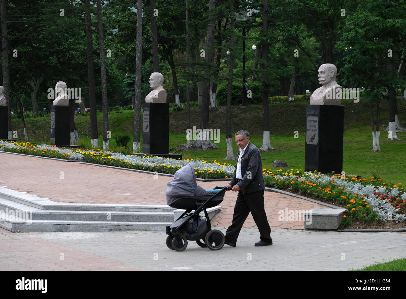 A pedestrian pushes a baby stroller as he pass by busts of Russian ...
