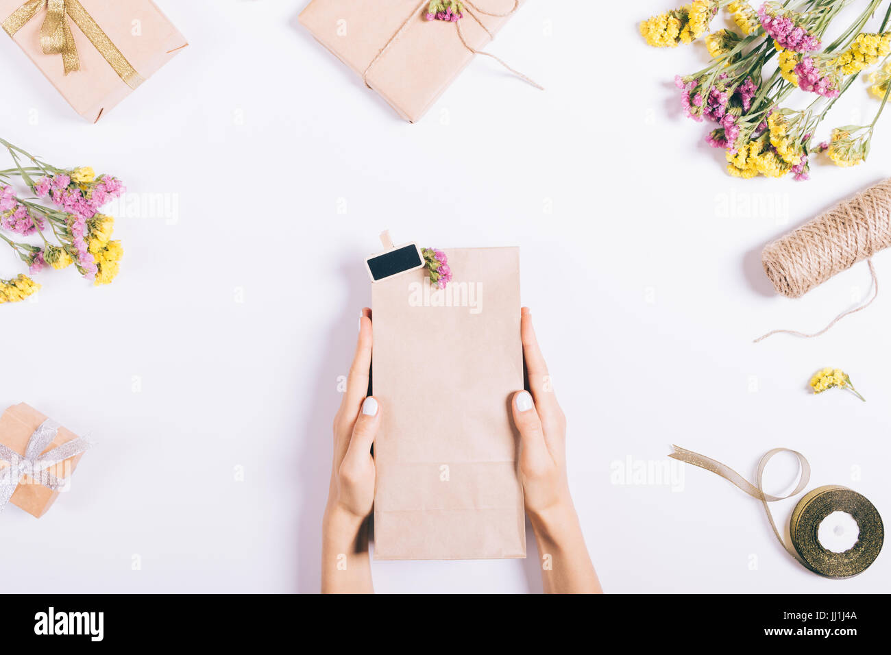 Female hands holding a package with a gift on a white table with ...