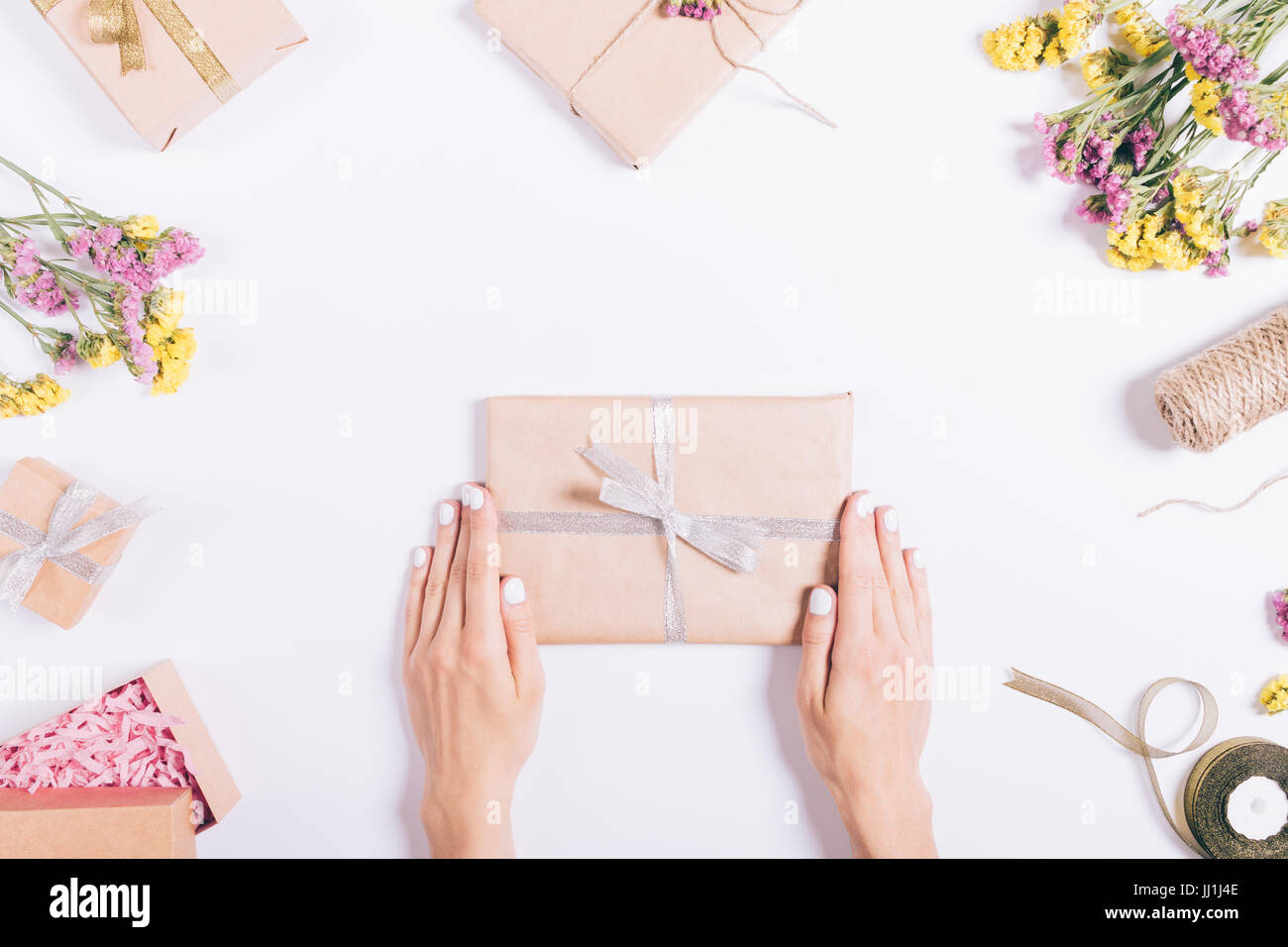 Female hands holding a gift with a ribbon on a white table with ...