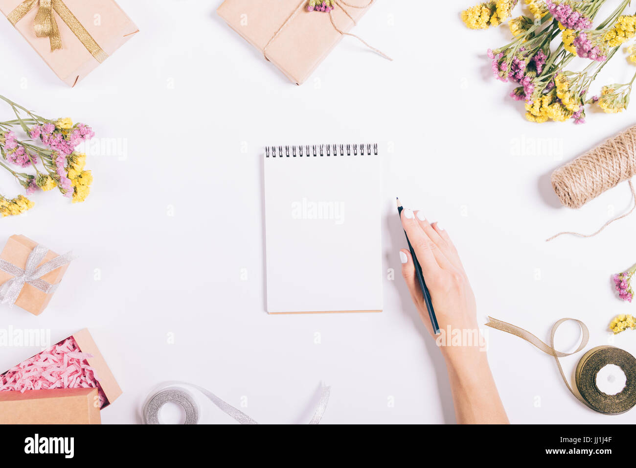 Female hand writing in a paper notebook on a white table with ...