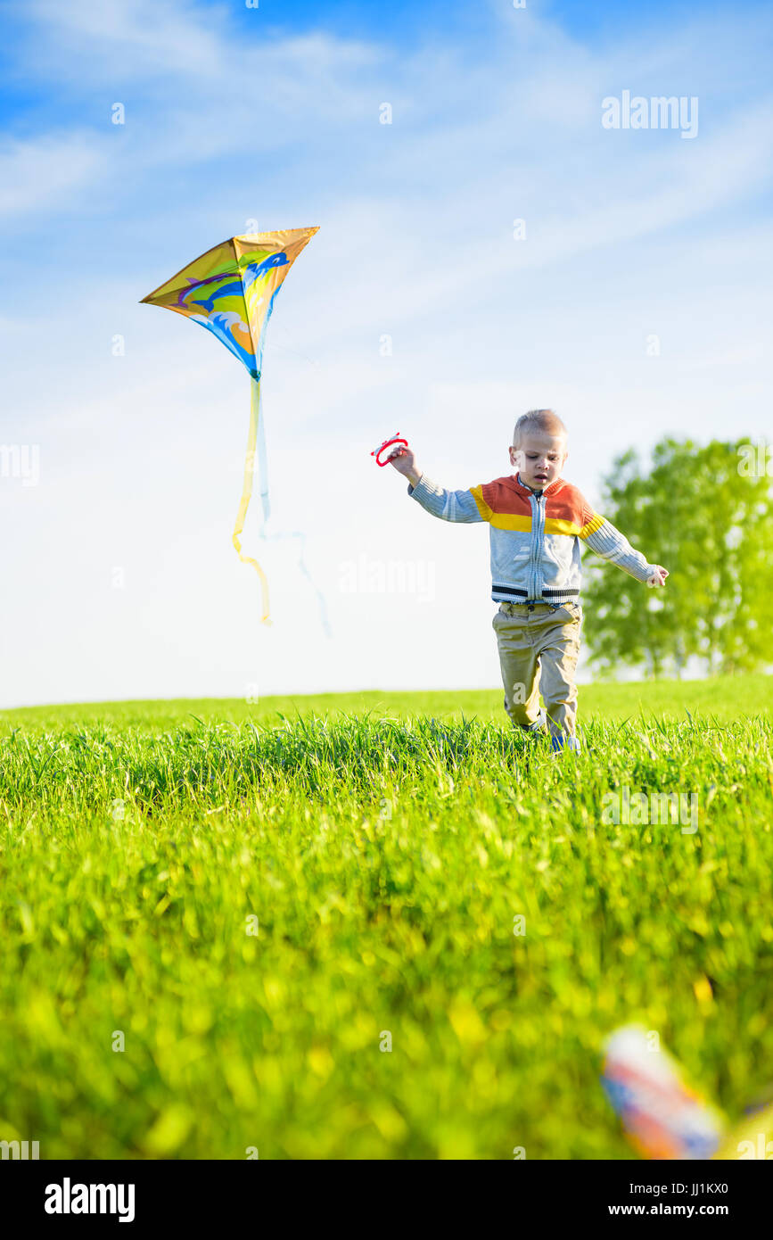 Young boy playing with his kite in a green field Stock Photo - Alamy