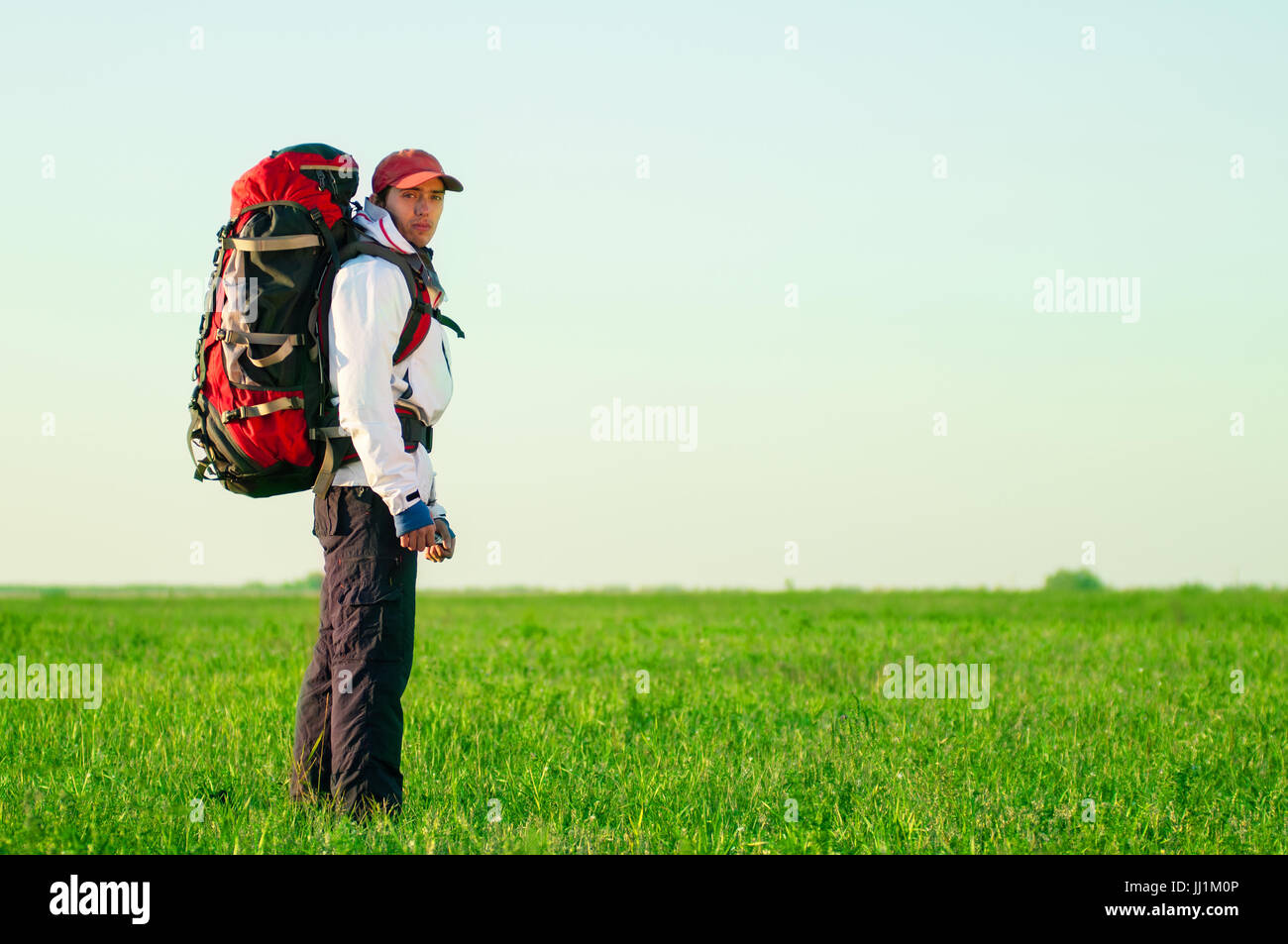 Hiker with backpack standing in the field Stock Photo - Alamy