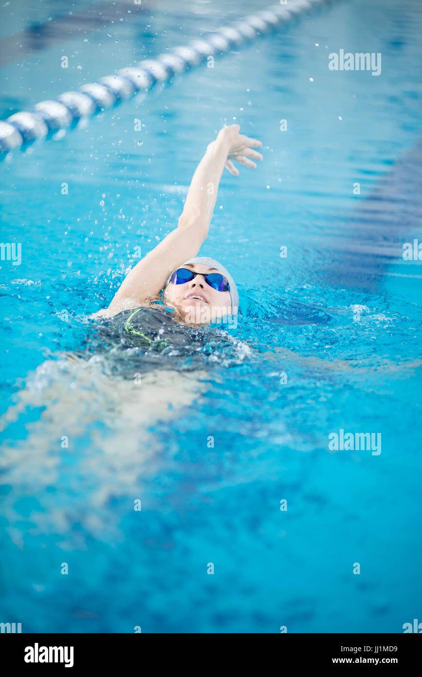 Young girl in goggles swimming back crawl stroke style Stock Photo - Alamy