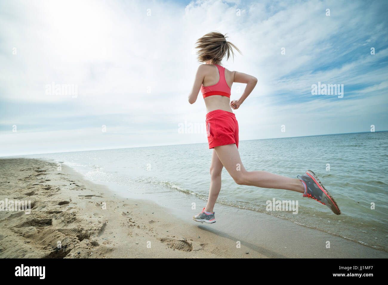 Young lady running at the sunny summer sand beach. Workout. Jog Stock ...