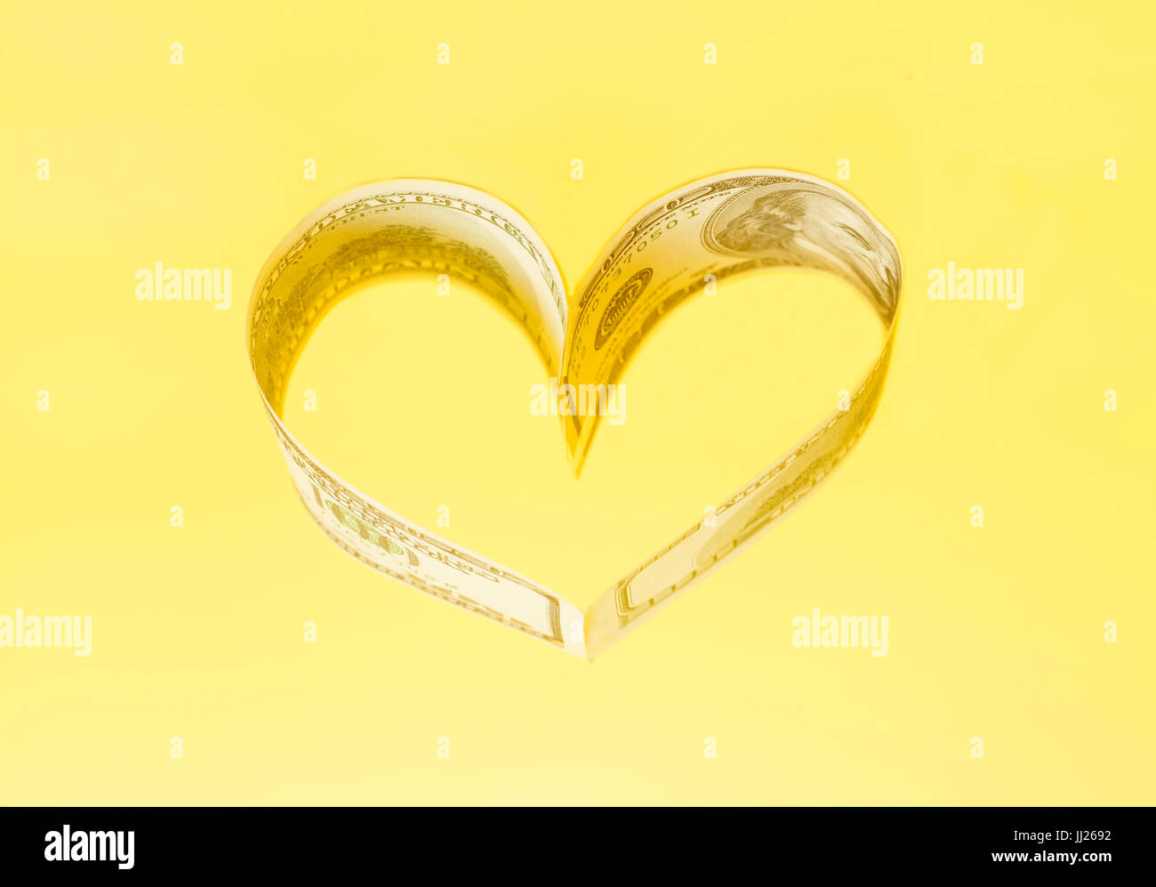 Dollar US bills in heart shape on yellow Stock Photo - Alamy