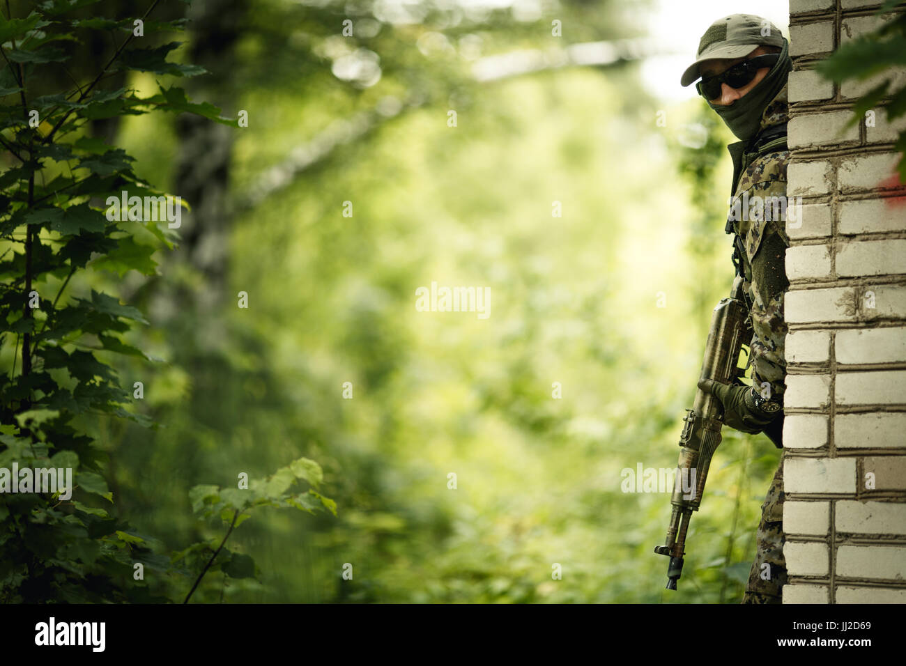 Soldier hides behind brick wall Stock Photo - Alamy