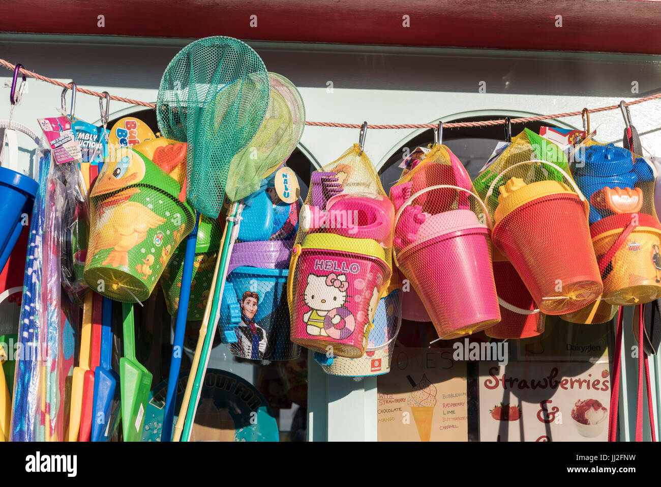 Buckets, spades and fishing nets hanging up for sale at a seaside shop ...