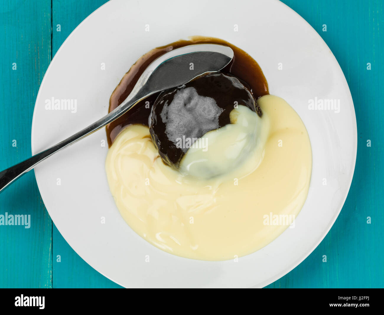 Sticky Toffee Pudding Dessert Served With Hot Custard Against a Blue ...