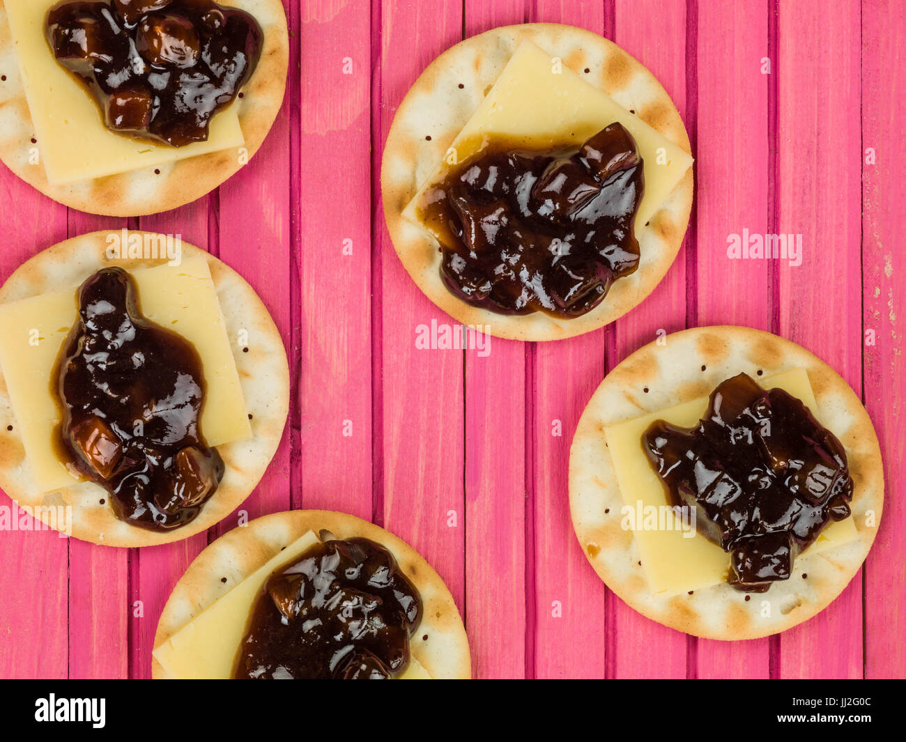 Cheese and Pickle on Biscuit Crackers Against a Pink Wooden Background ...