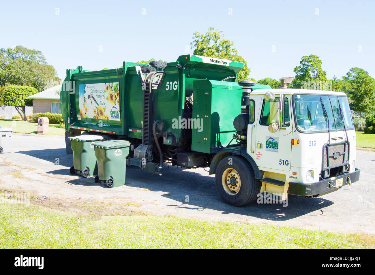 A garbage truck sitting beside two green trashcans Stock Photo - Alamy