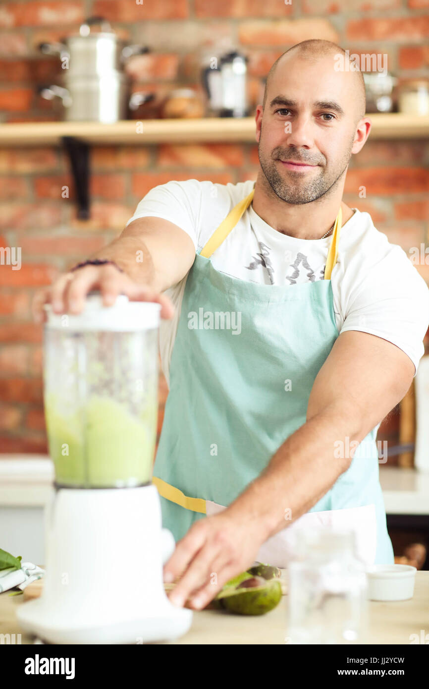 Cuisine. Man at kitchen in blue apron Stock Photo - Alamy
