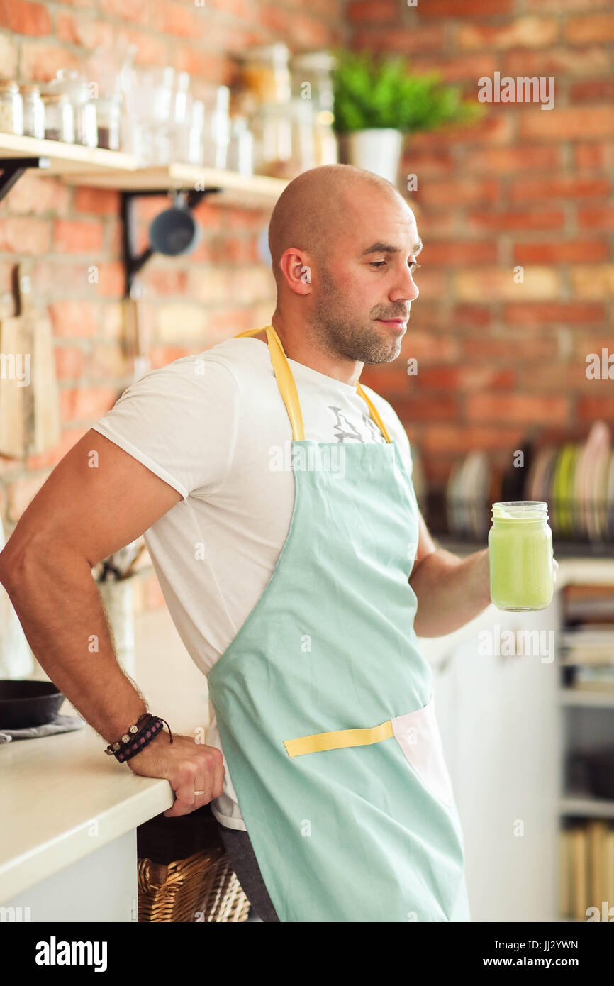 Cuisine. Man at kitchen in blue apron Stock Photo - Alamy