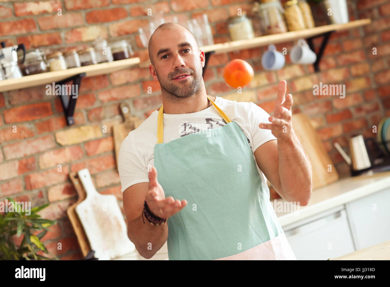 Cuisine. Man at kitchen in blue apron Stock Photo - Alamy