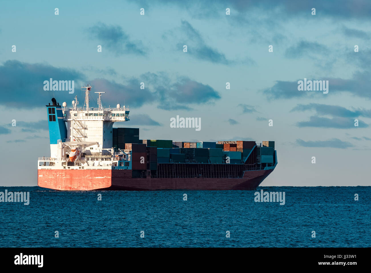 Full red container ship moving in still water Stock Photo - Alamy