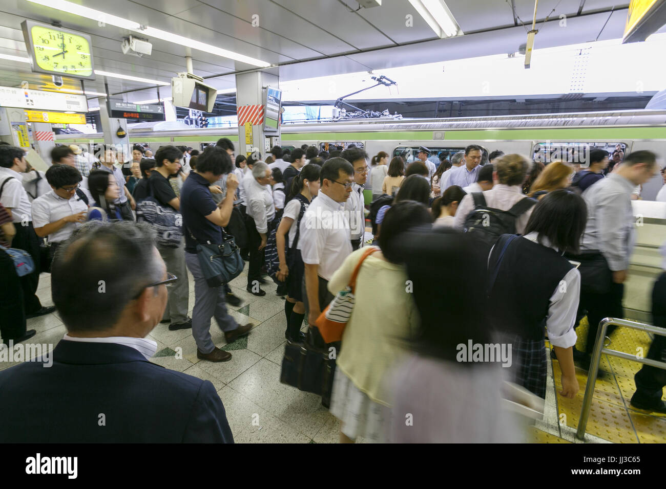 Commuters try to board the train during the peak-hour at Shibuya ...