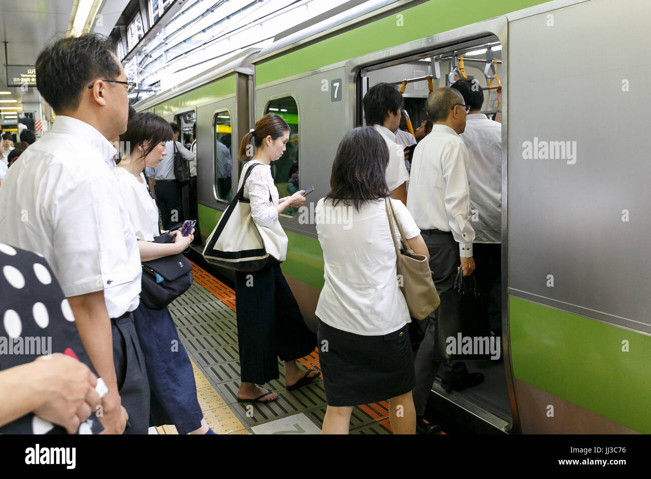 Commuters try to get into crowded train at Shibuya Station on July 18 ...
