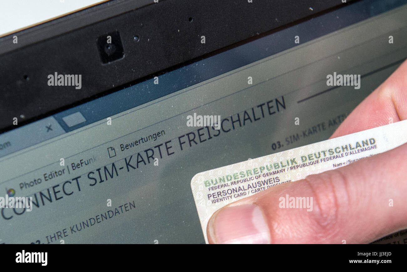 A man holds his German ID card in front of the camera of a laptop ...