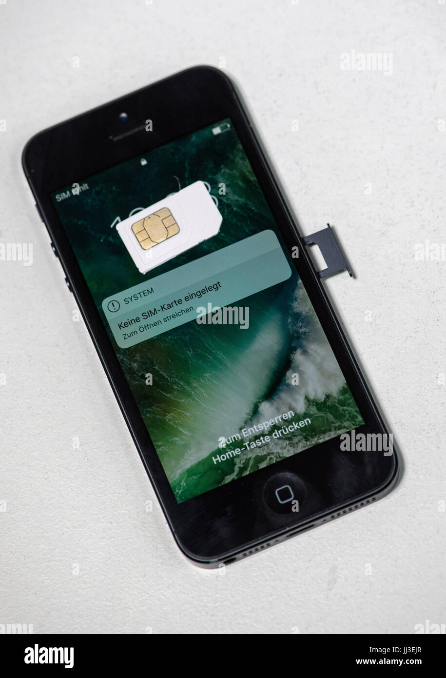 A SIM card lies on the screen of a mobile phone currently displaying a ...