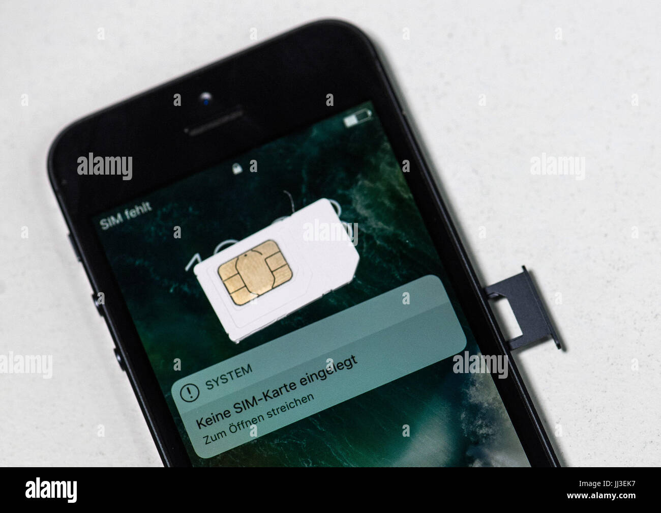 A SIM card lies on the screen of a mobile phone currently displaying a ...