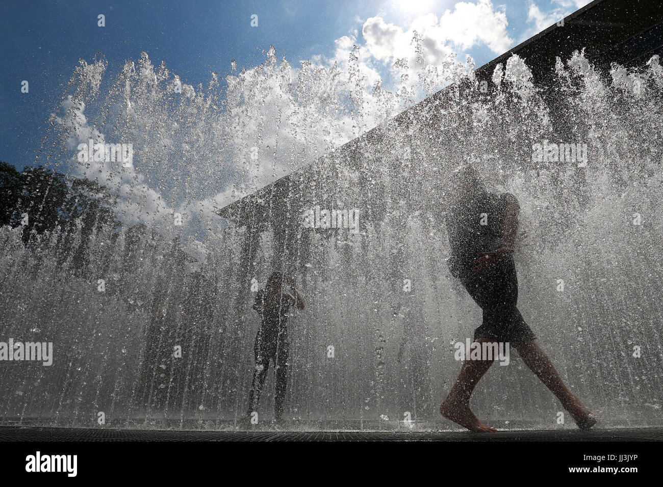Teenagers run through the water installation 'Hexagonal Water Pavilion ...