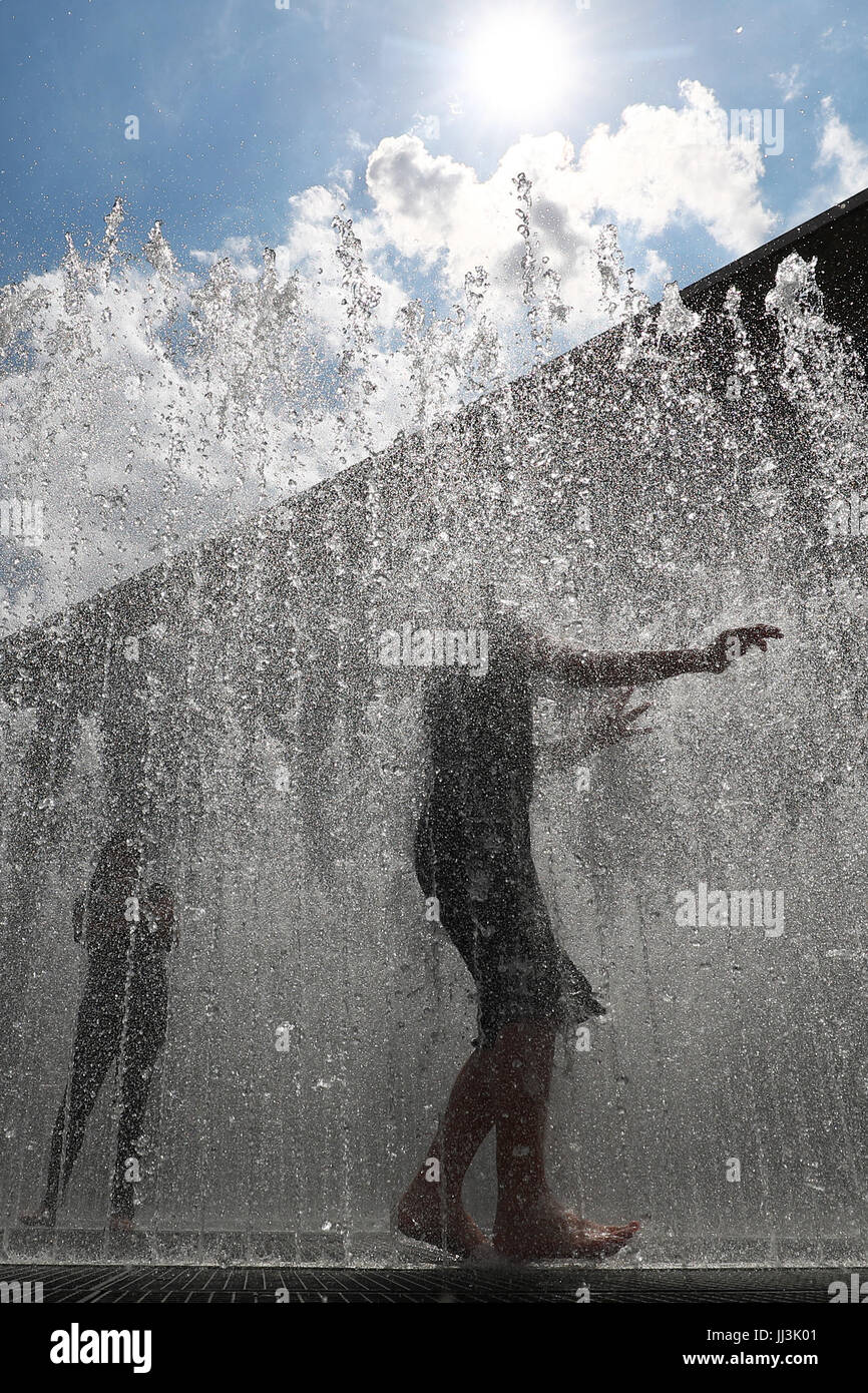 Teenagers run through the water installation 'Hexagonal Water Pavilion ...