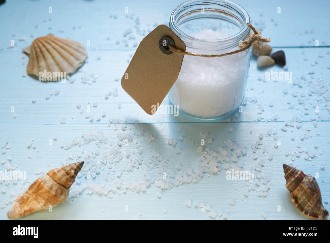 small jar of sea salt with carton cardboard tag on blue desk with a few ...
