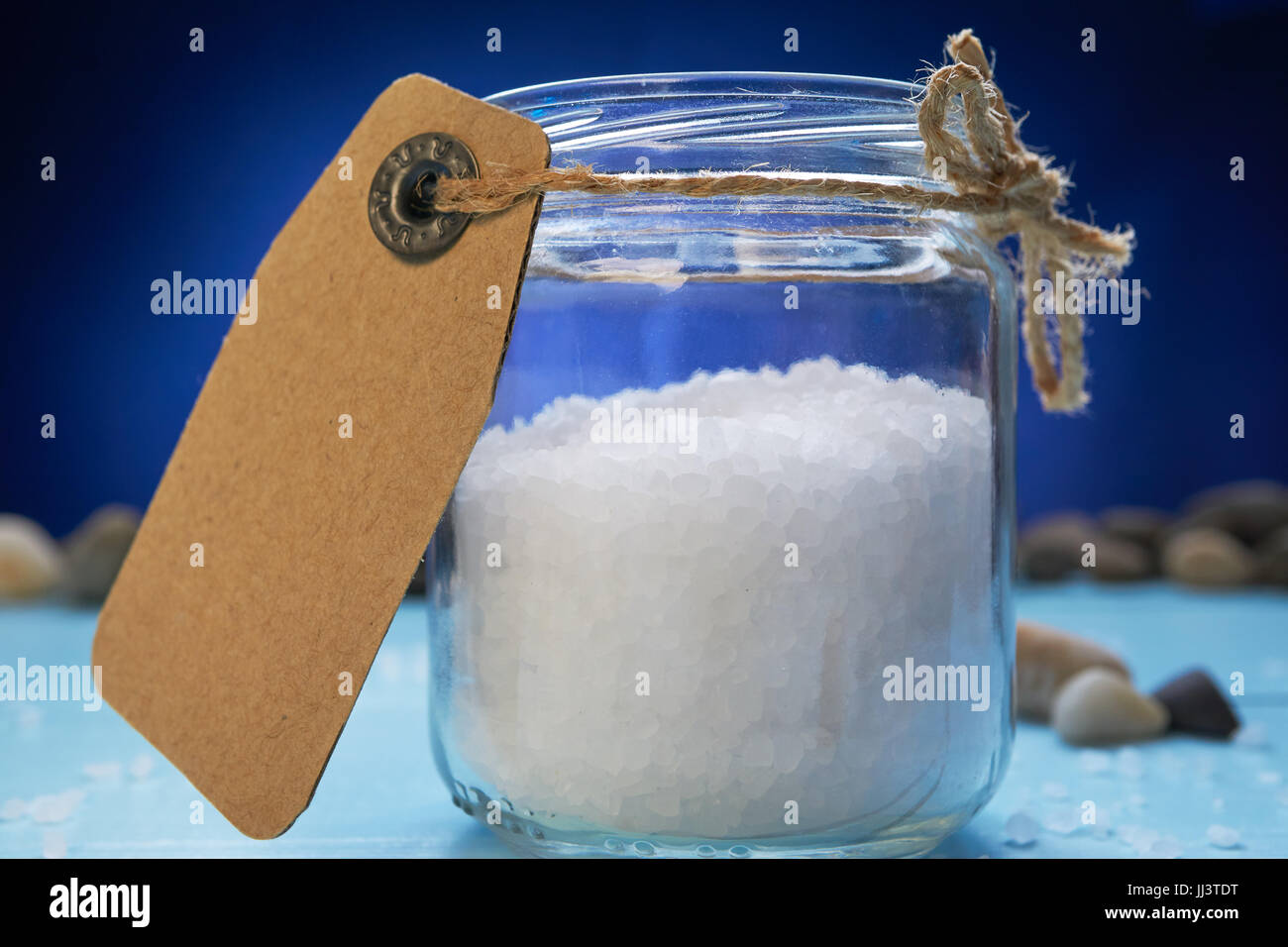 closeup of small jar with sea salt with carton cardboard empty tag on ...