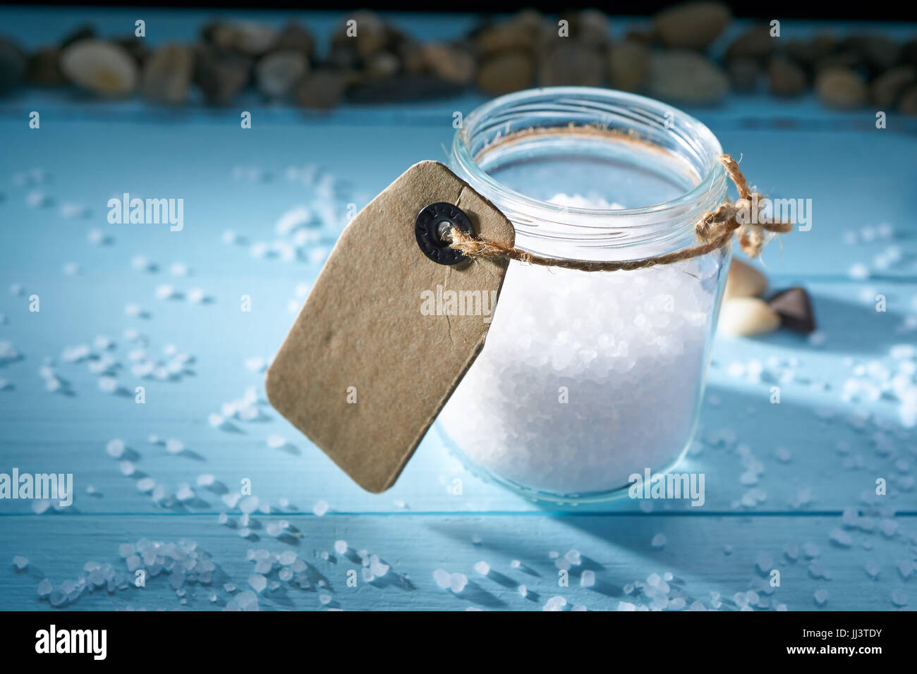 closeup of small jar with sea salt with carton cardboard empty tag on ...