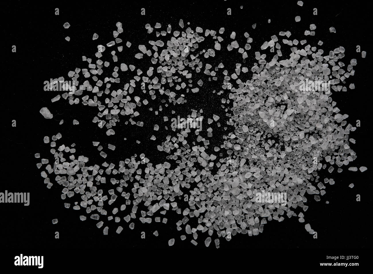sea salt crystals scattered all over the black desk. view from top ...