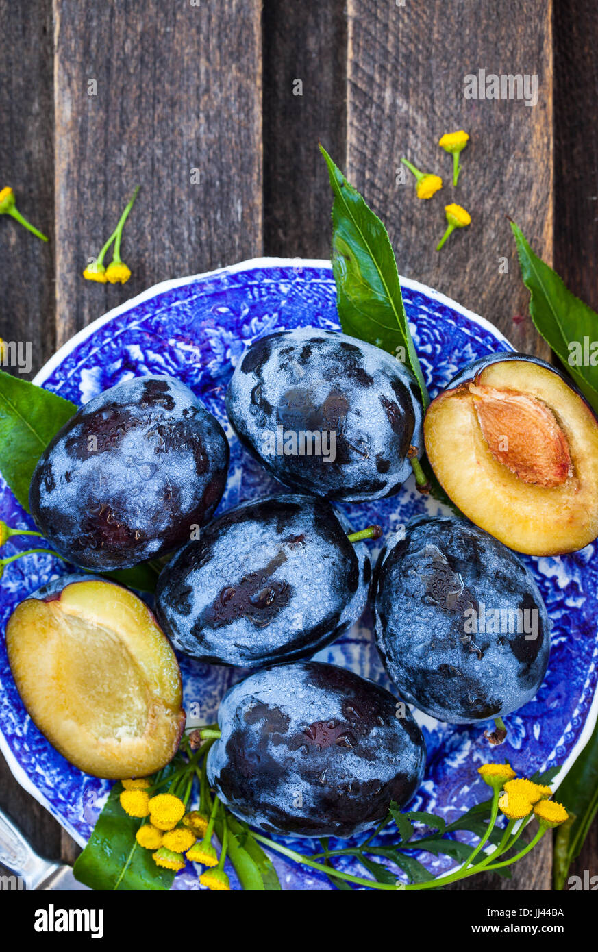 Fresh ripe blue plums on plate, wooden table, top view Stock Photo - Alamy