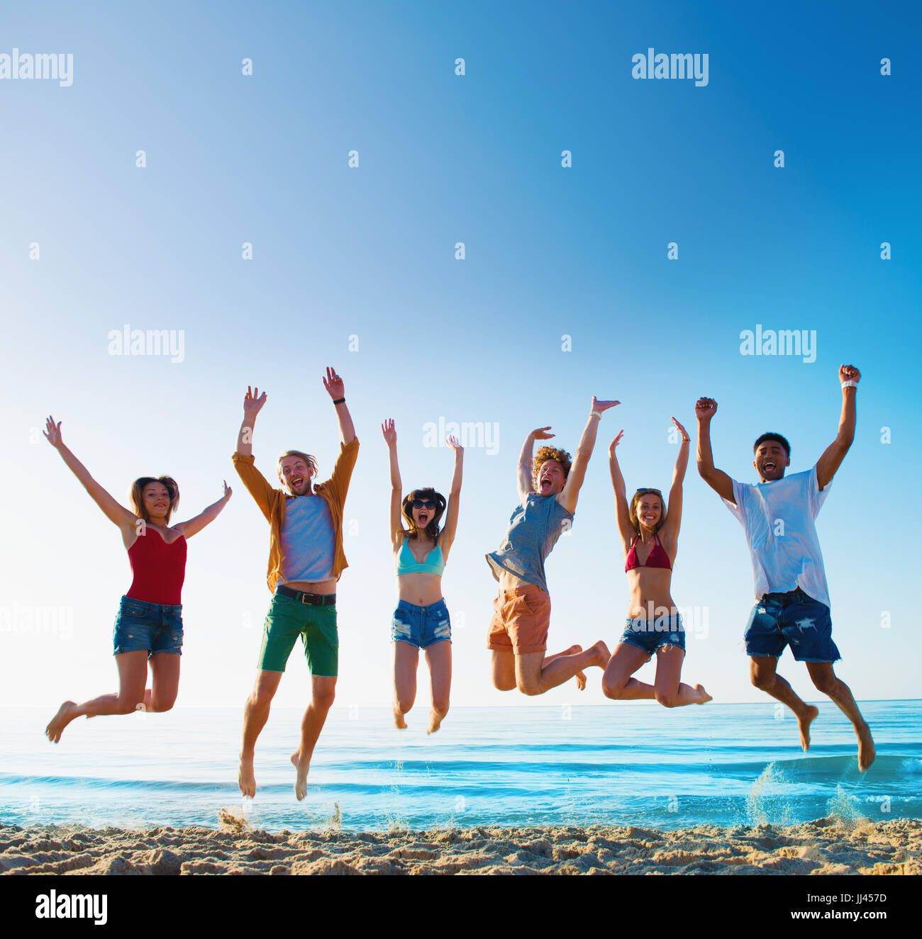 Happy smiling friends jumping at the beach Stock Photo - Alamy