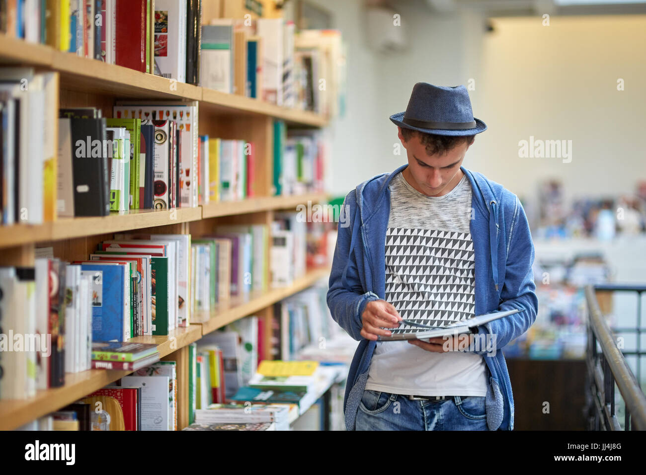 Young man picking a book from a public library Stock Photo - Alamy