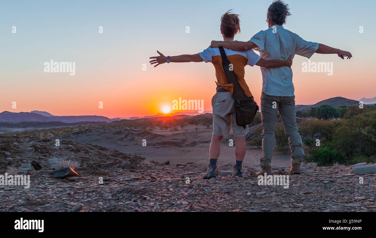 Hugging couple with outstretched arms watching the stunning view of the ...