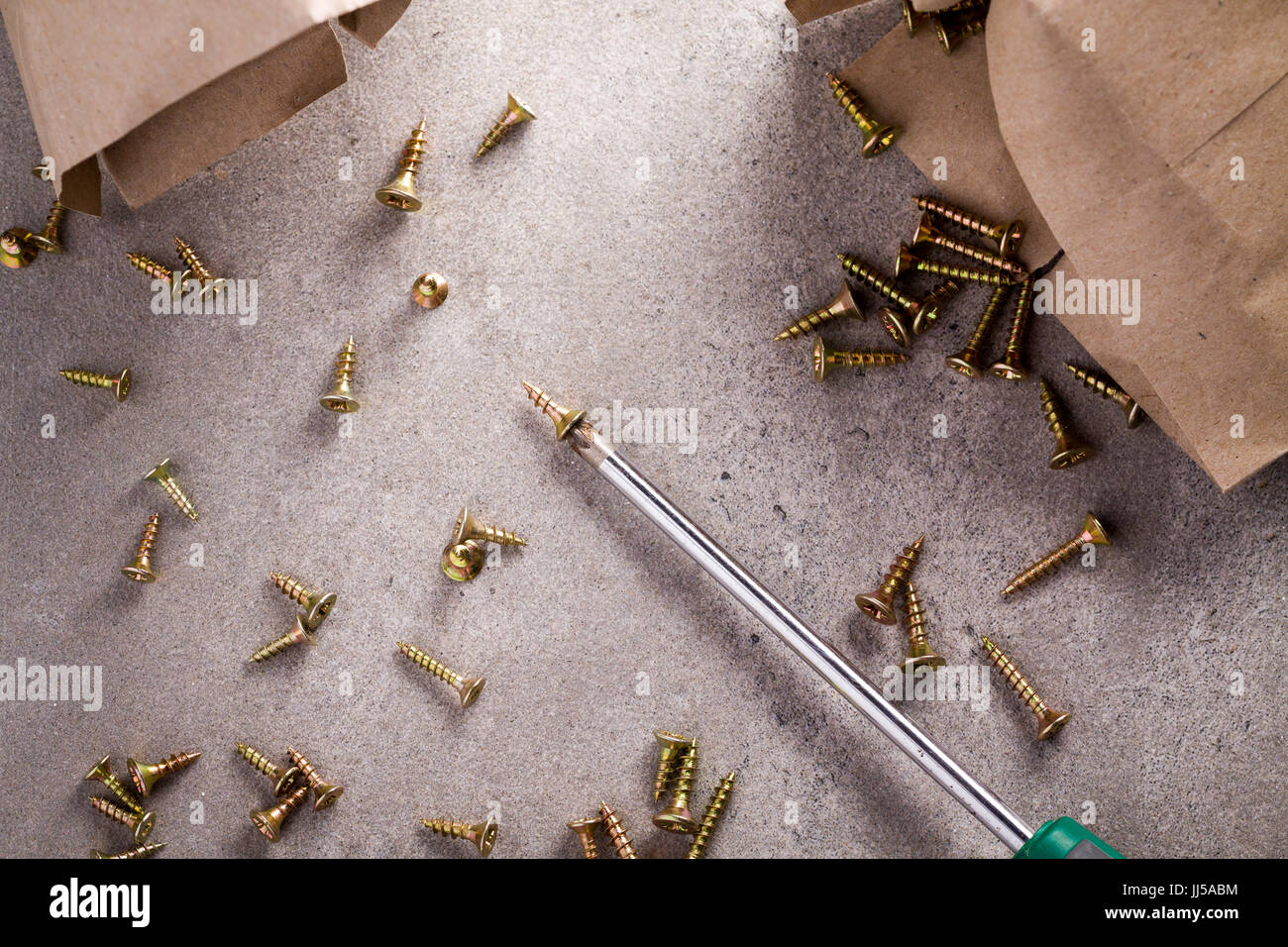 Scattered small screws from paper bag and screwdriver lying on the ...