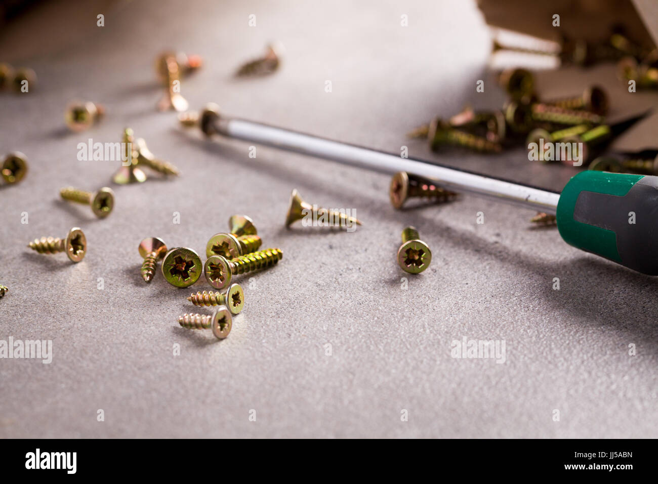 Scattered small screws from paper bag and screwdriver lying on the ...