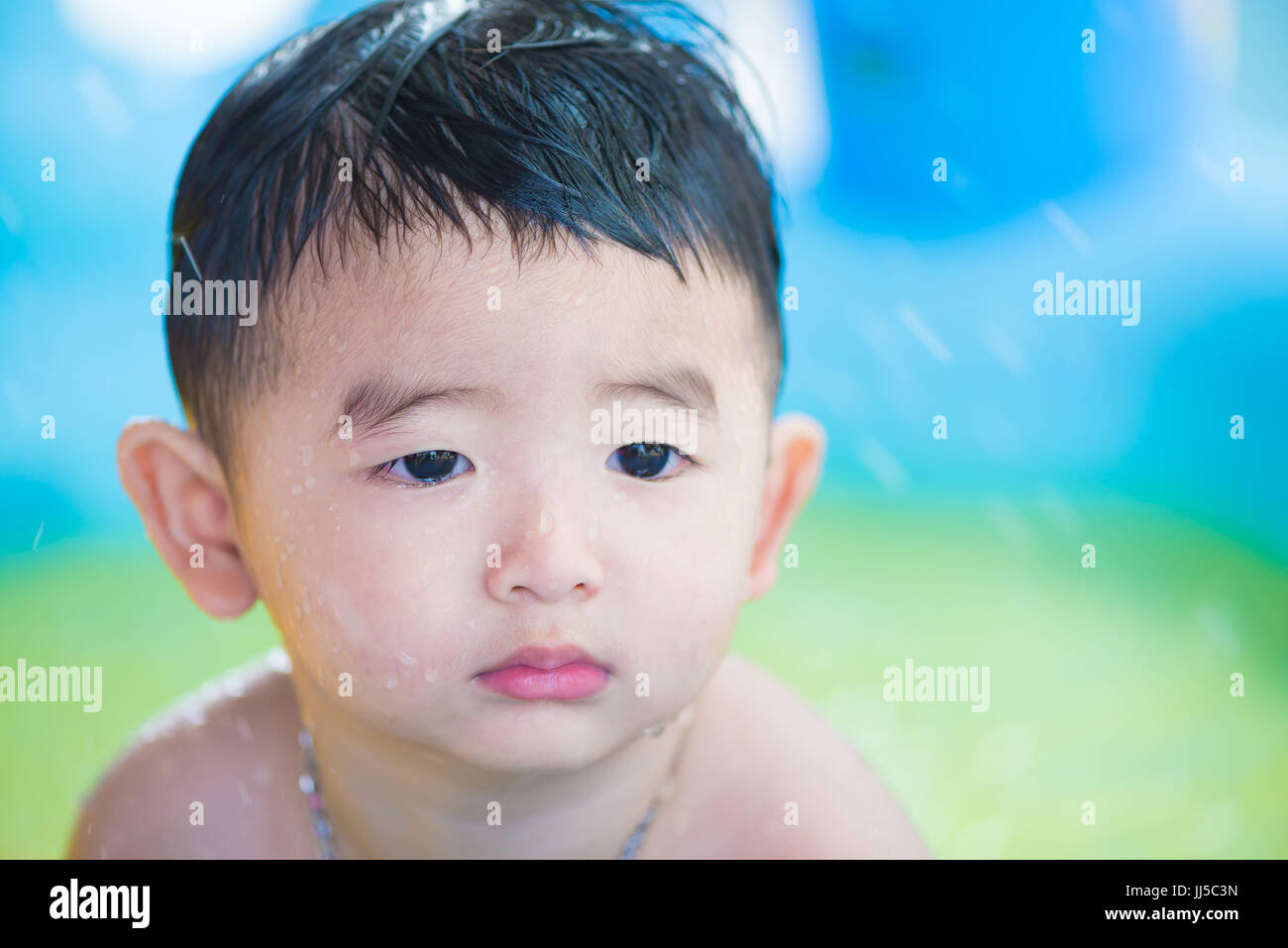 Sad Asian kid playing alone in inflatable baby pool. Boy swim and ...