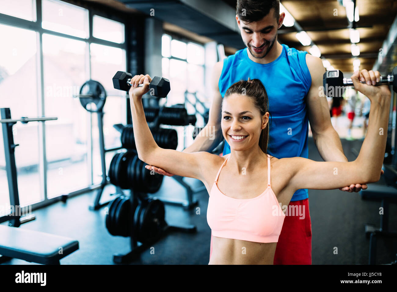 Beautiful woman doing exercises in gym with personal trainer Stock ...