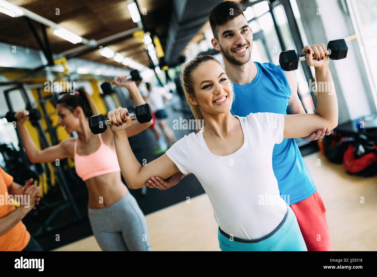 Beautiful woman doing exercises in gym with personal trainer Stock ...