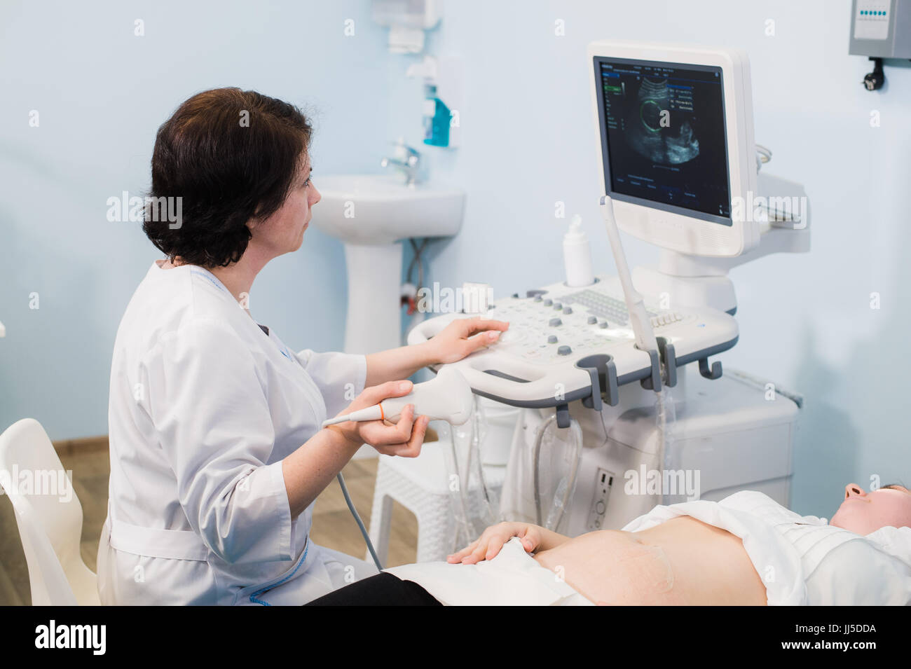 Doctor using ultrasound equipment screening hi-res stock photography ...