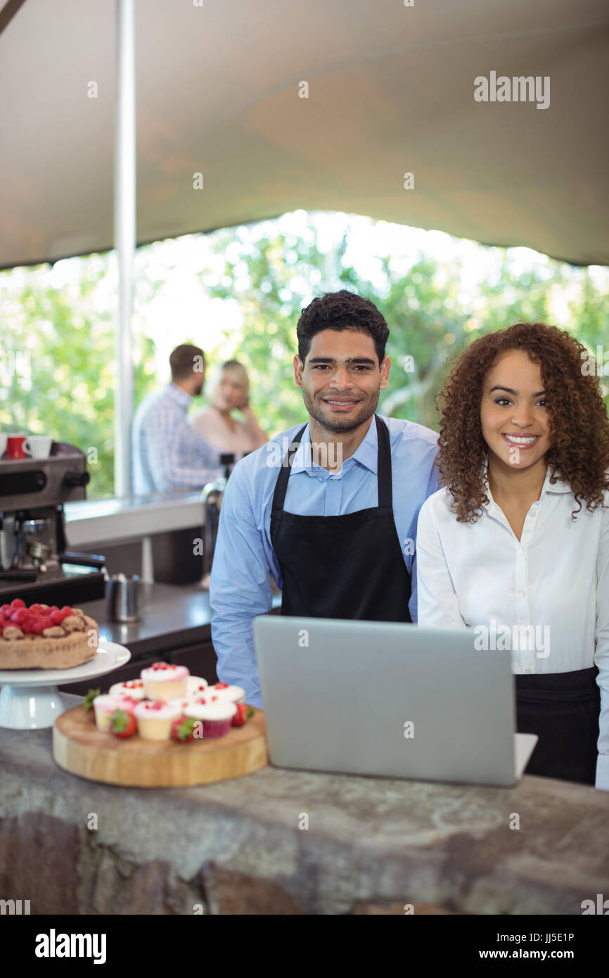 Male waiter and female waitress with laptop at outdoor restaurant Stock ...