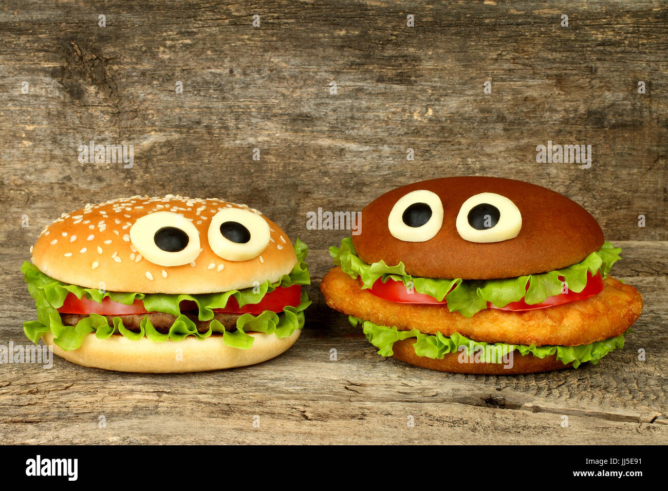 Two big funny hamburgers whith cheese eyes and chicken cutlet on wooden ...
